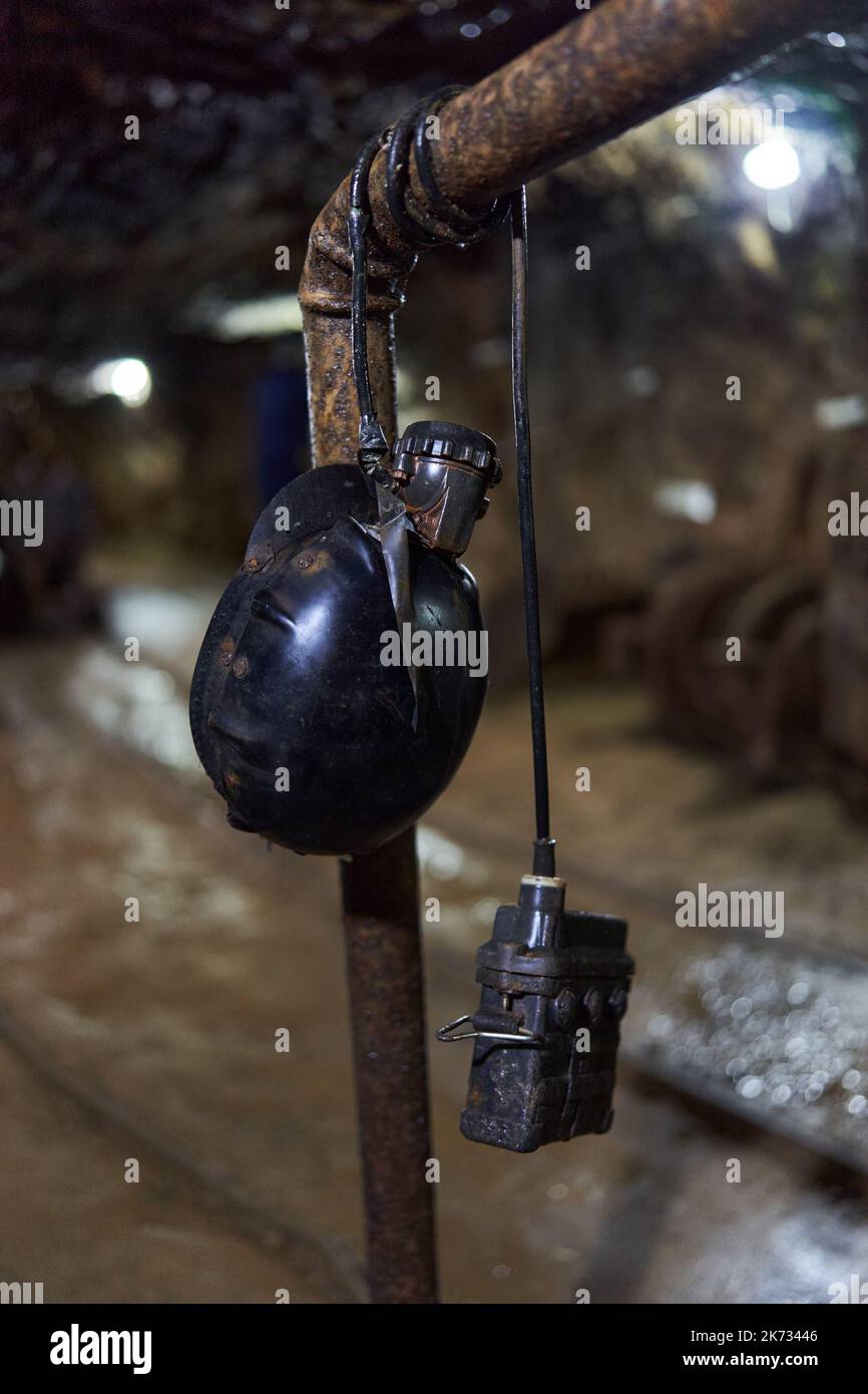 Old miner helmet with torch and battery hanging on a rail in an ...