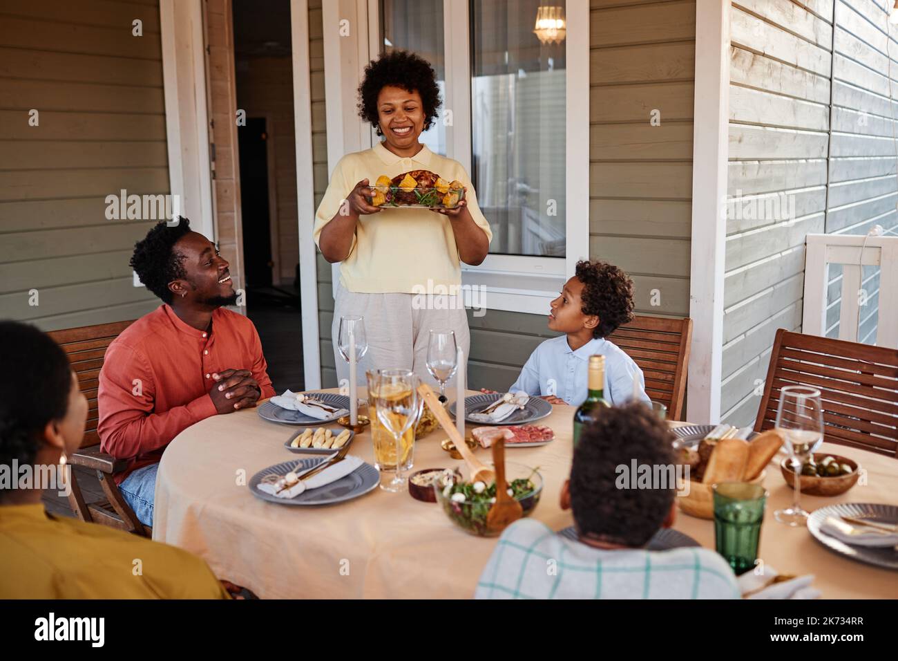 Portrait of senior black woman bringing food to table while enjoying ...