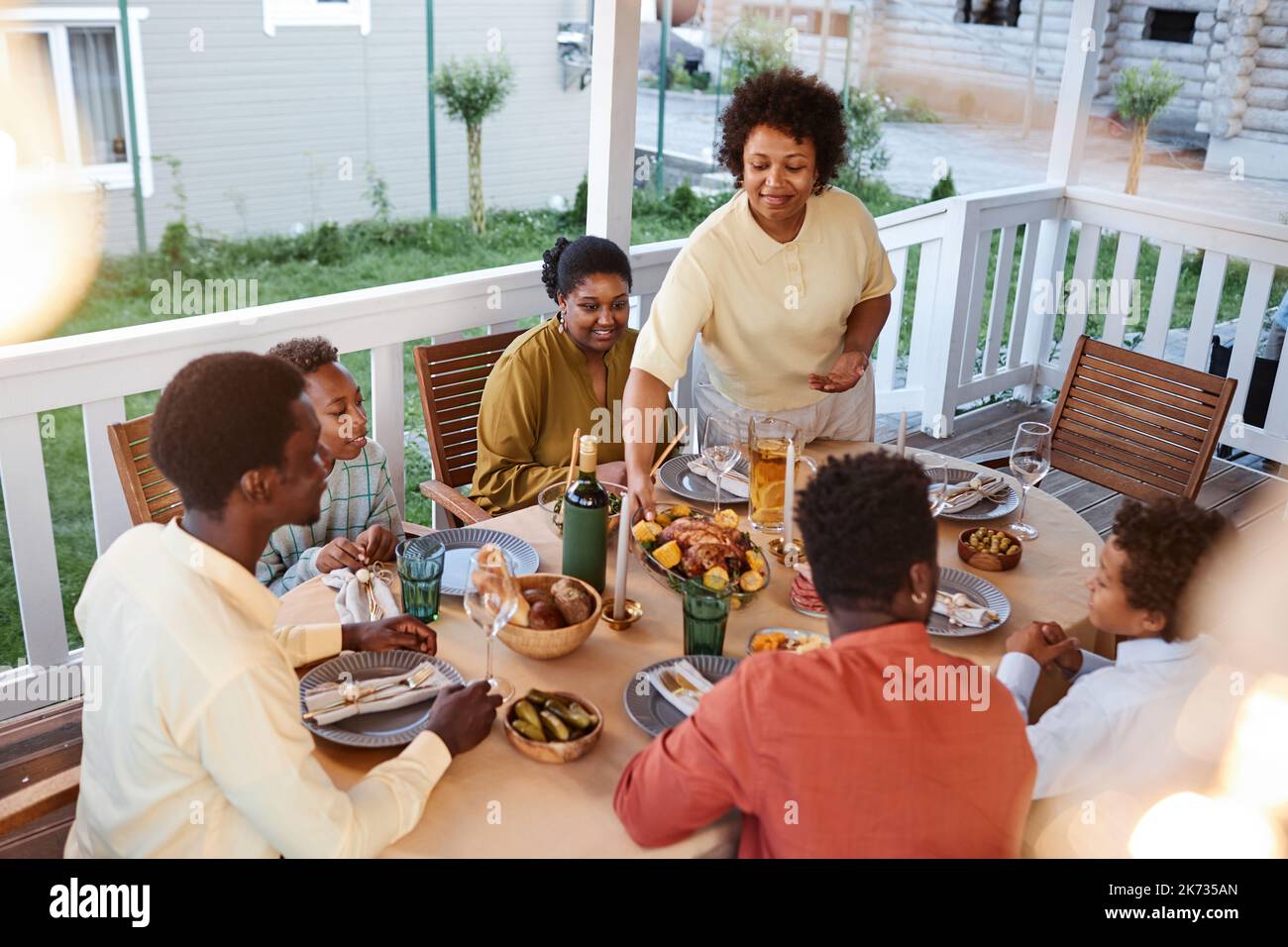 African American family at dinner table outdoors with smiling woman ...