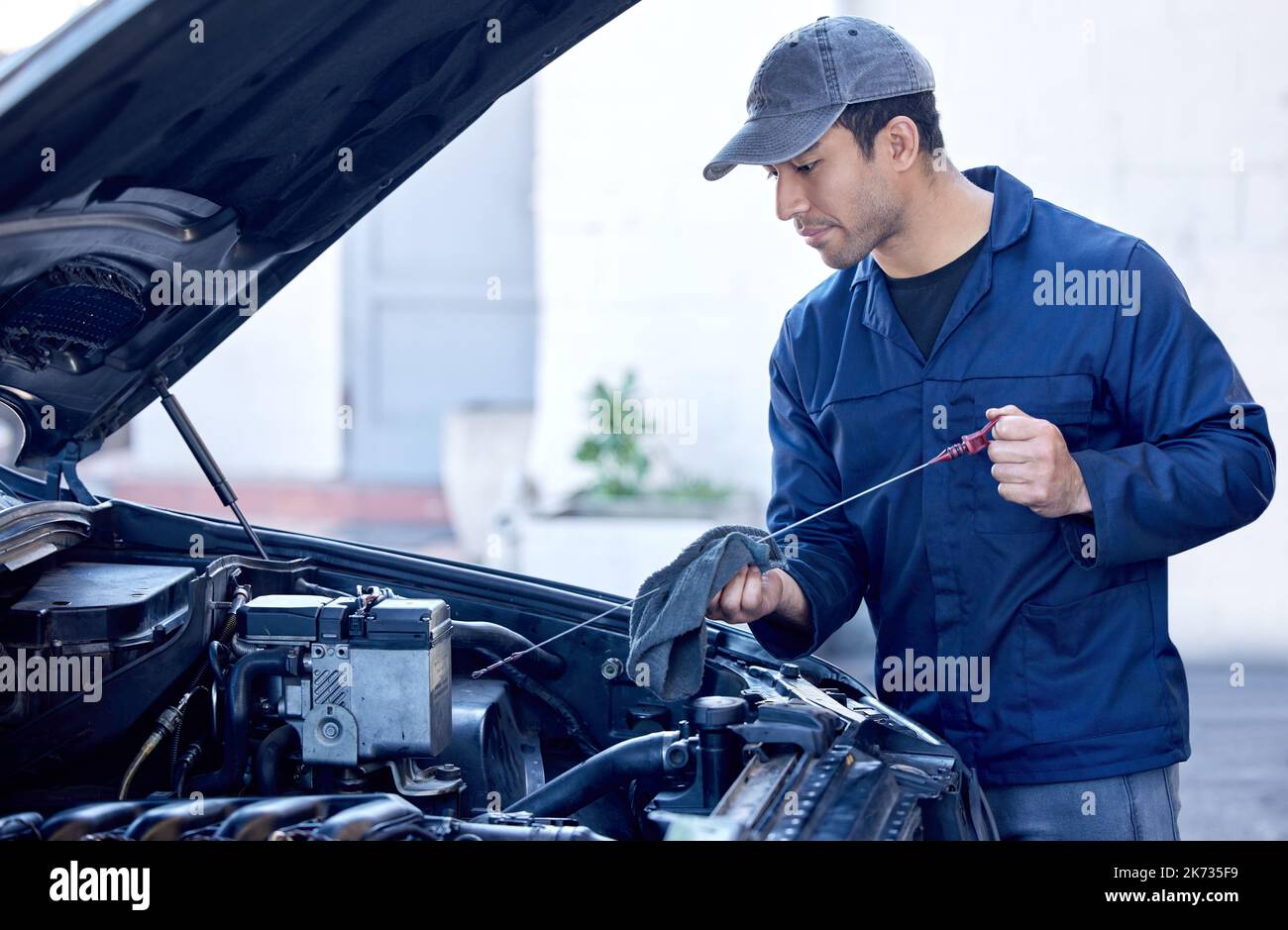 Checking the oil levels. a handsome young male mechanic working on the ...