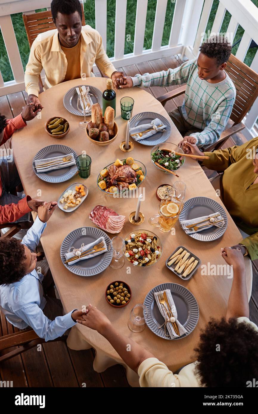 Top view of African American family saying grace at festive dinner ...