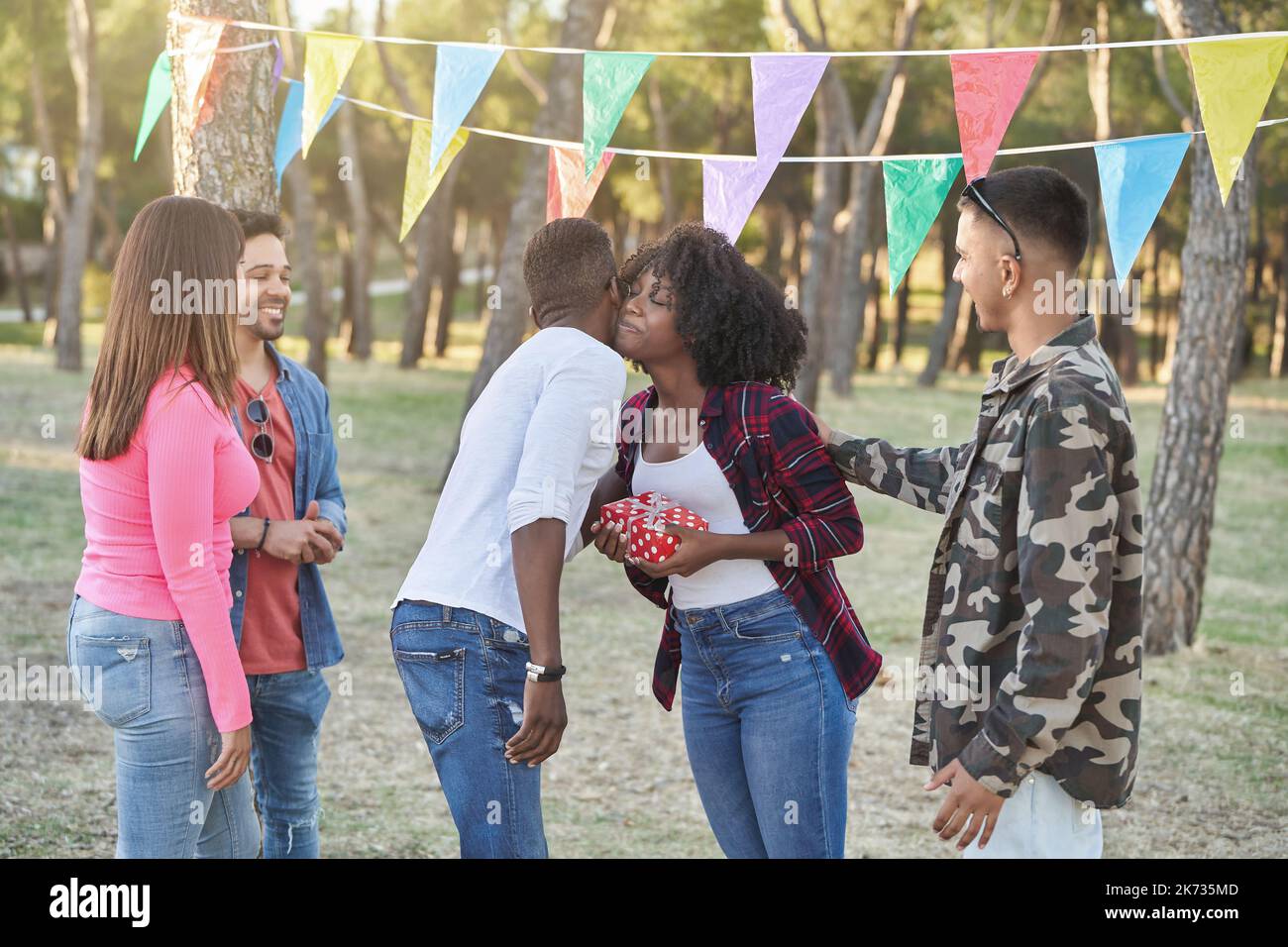 Group of friends giving a birthday present to their friend while ...