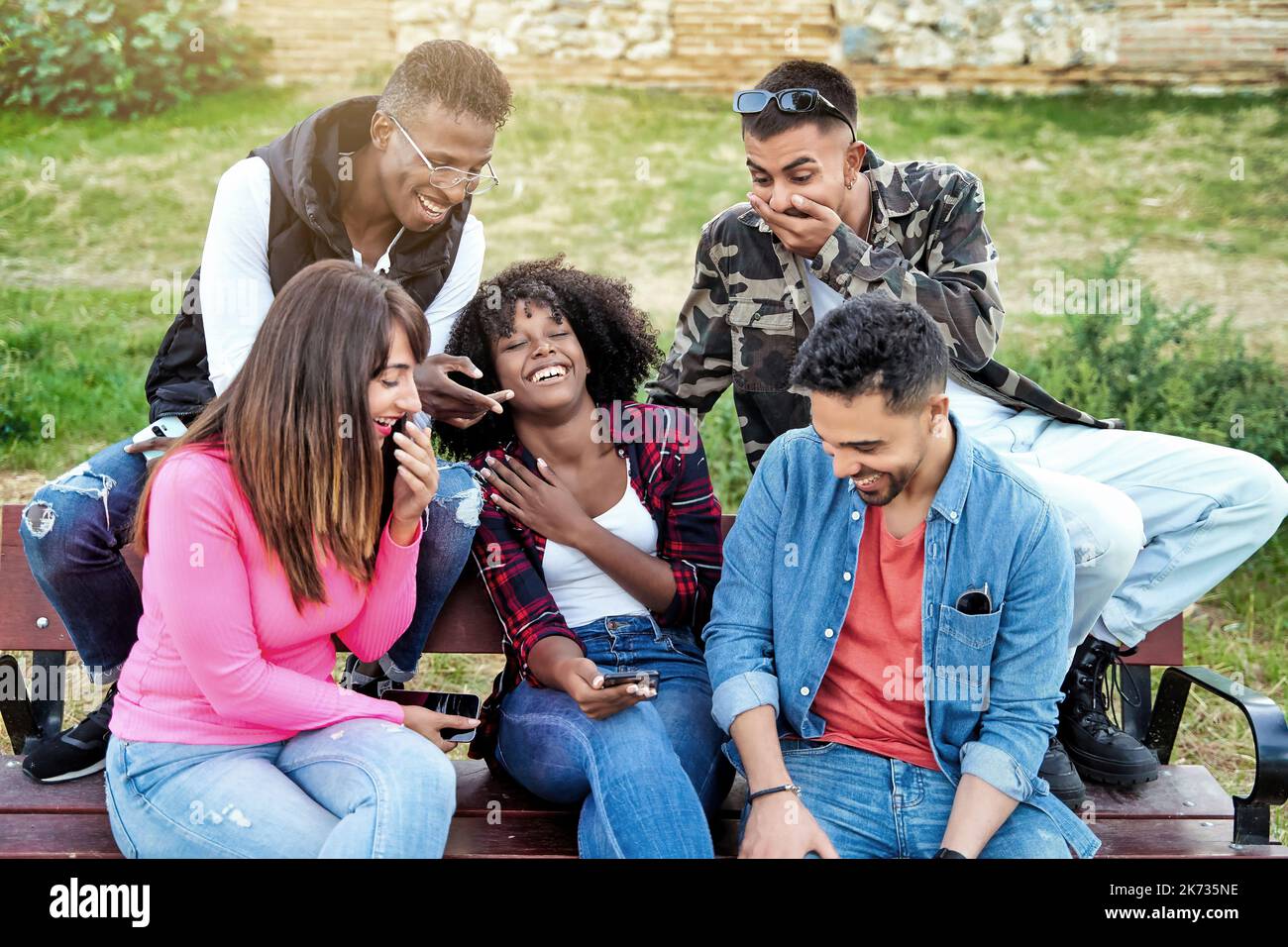 Multi-ethnic friends having fun and laughing while using a mobile phone ...