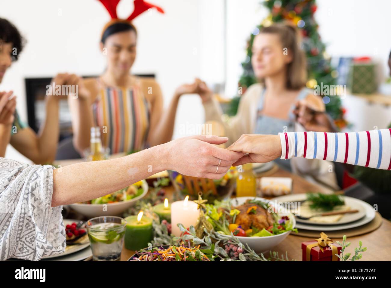 Happy diverse friends sitting at table and praying before dinner at ...