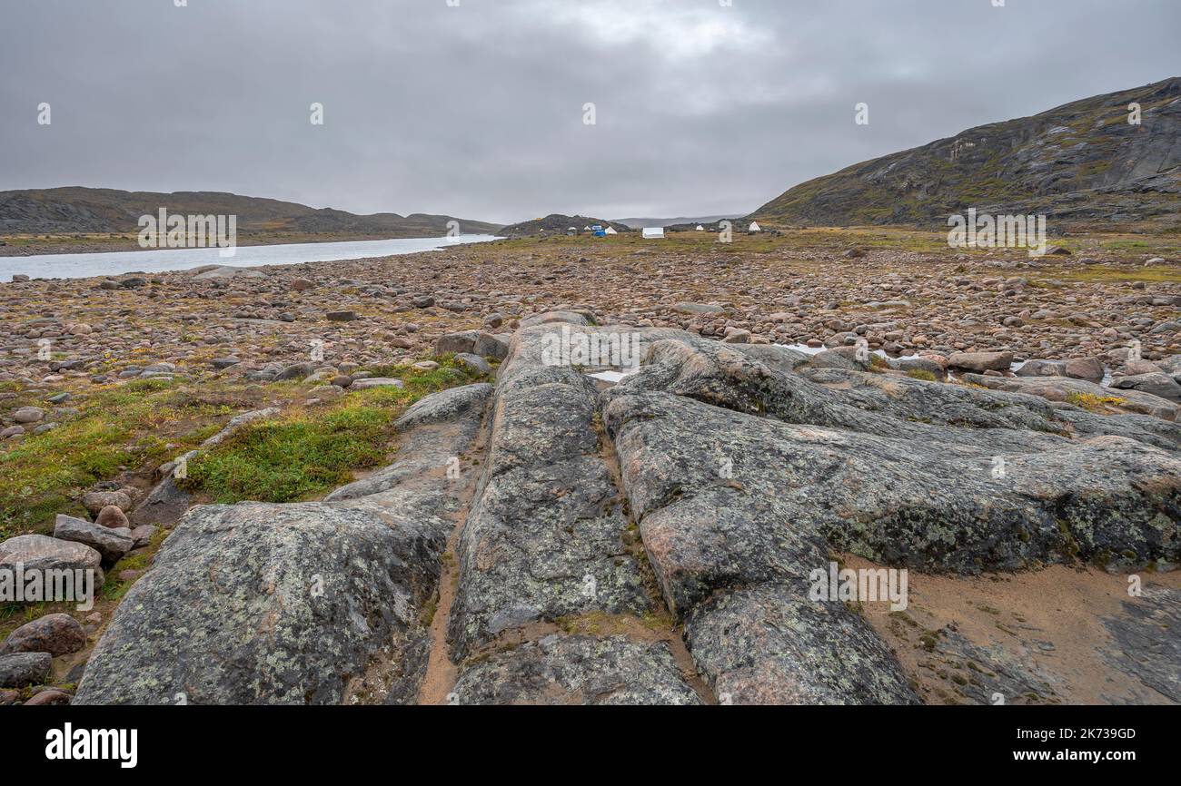 A distant group of camping tents beside the Sylvia Grinnell River in ...