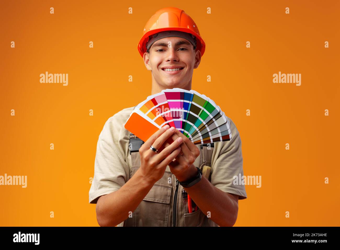 Handsome young worker in uniform holding paint samples palette on ...