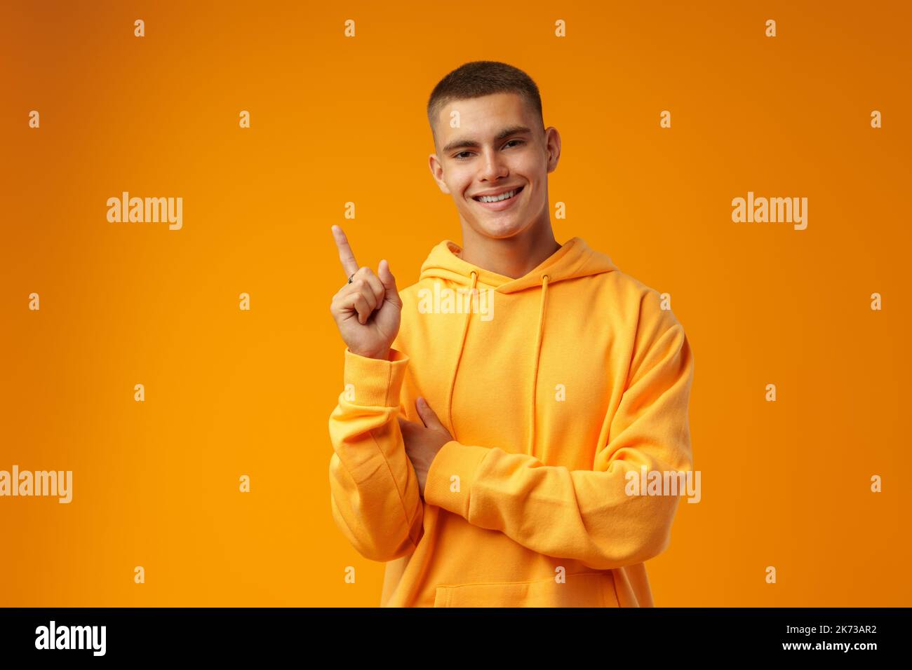 Handsome young man pointing to copy space on a yellow background Stock ...