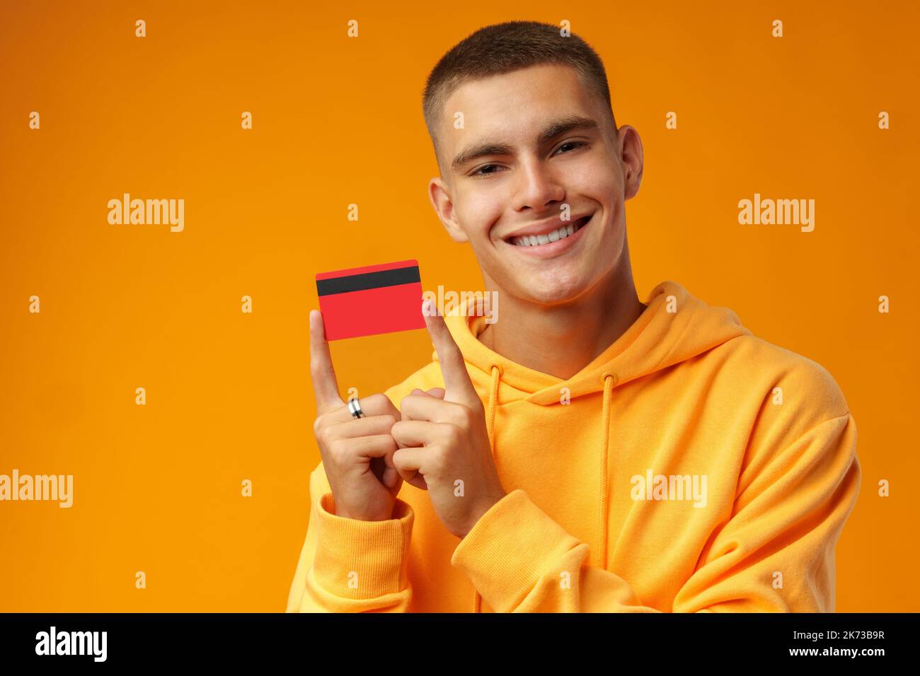 Handsome young man holding credit card on yellow color background Stock ...