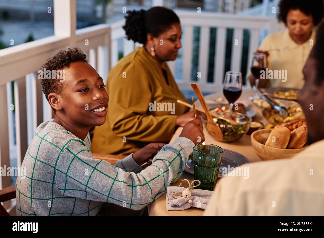 Side view portrait of smiling African American boy enjoying dinner with ...