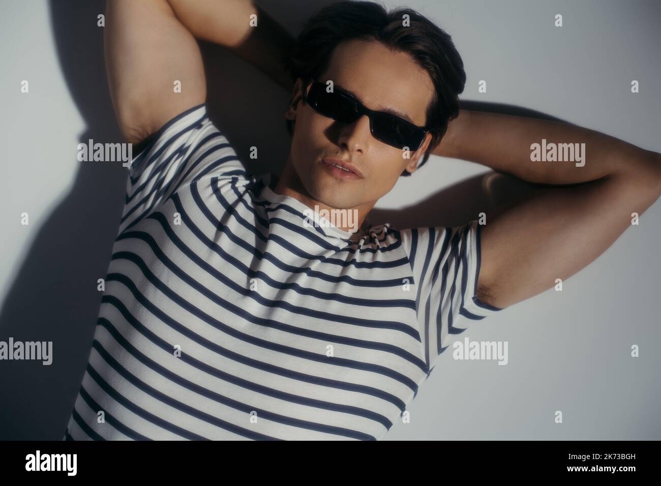 Top view of muscular man in sunglasses and t-shirt lying on grey ...