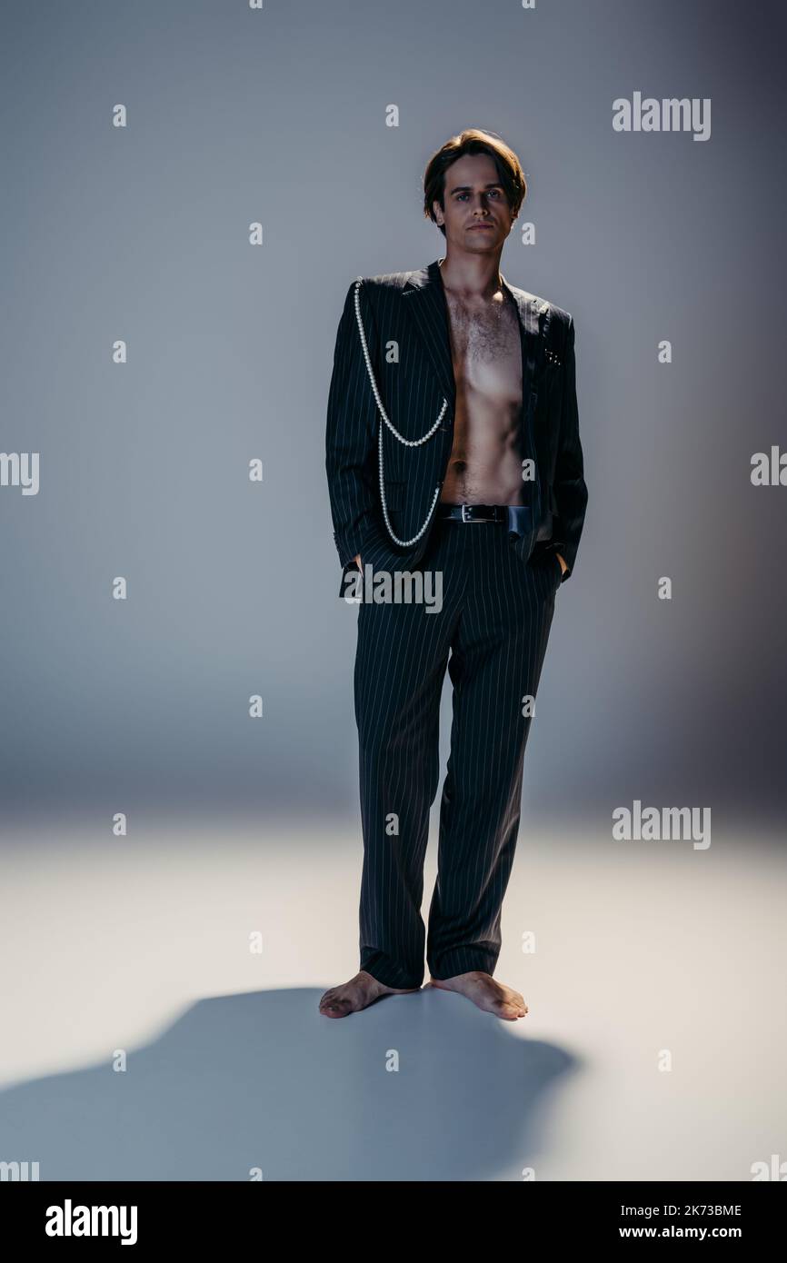 full length of man with hairy chest and stylish suit with pearl chain ...