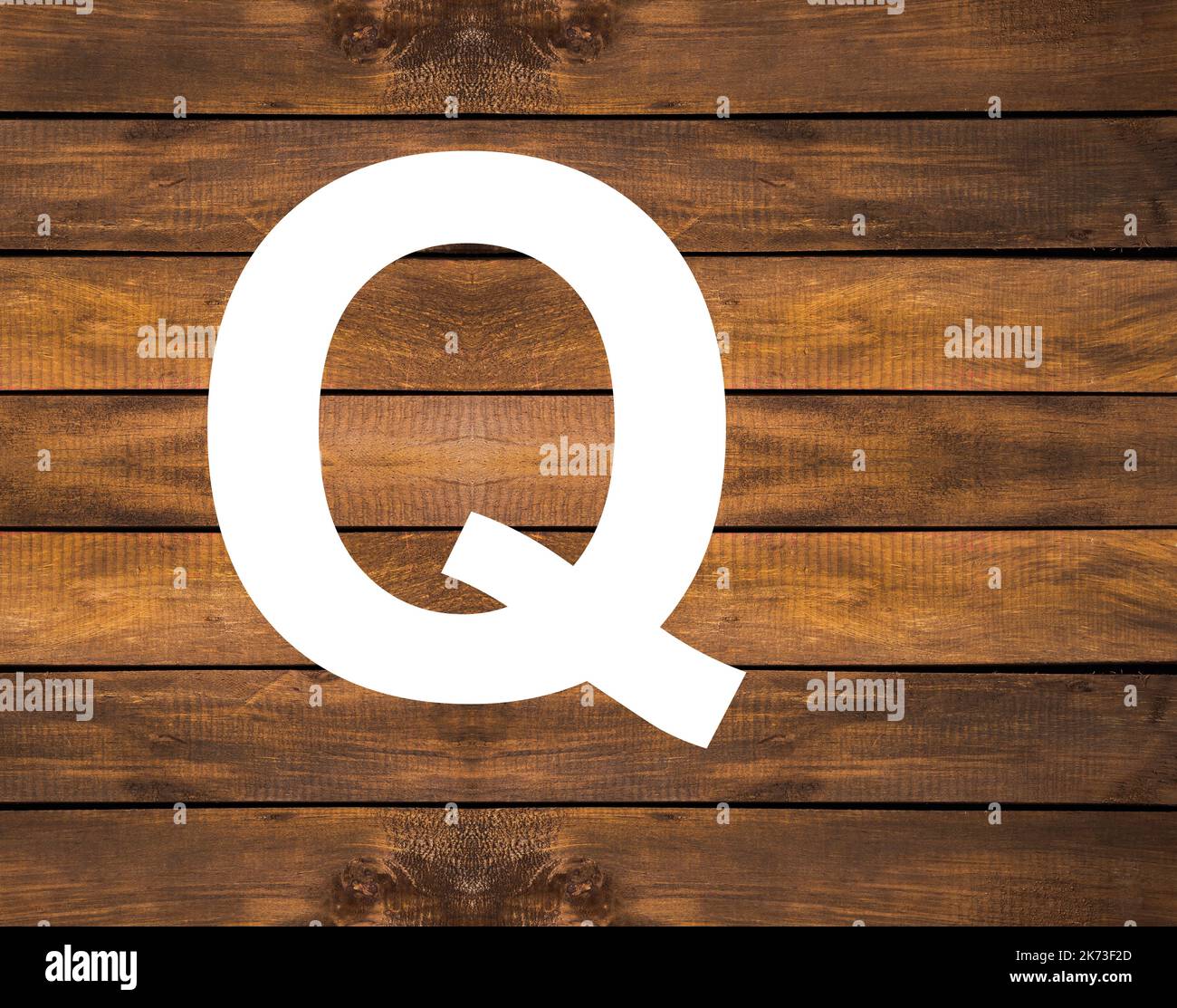 Q capital letter of alphabet in white hole on wood background Stock ...
