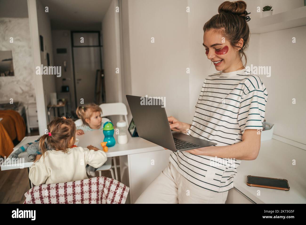 Working mom and her daughters in the kitchen Stock Photo - Alamy