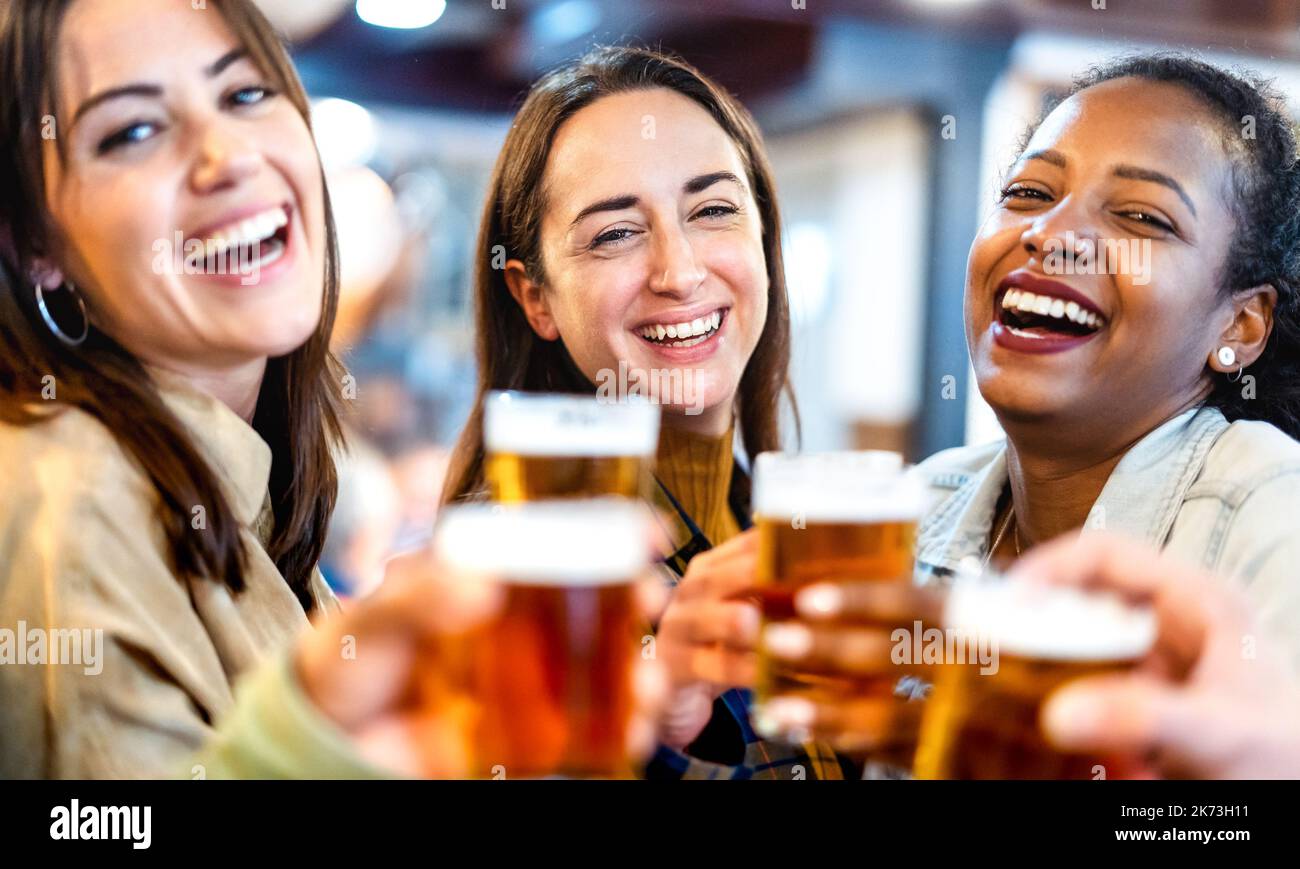 Multi cultural girl friends drinking beer at brewery bar restaurant ...