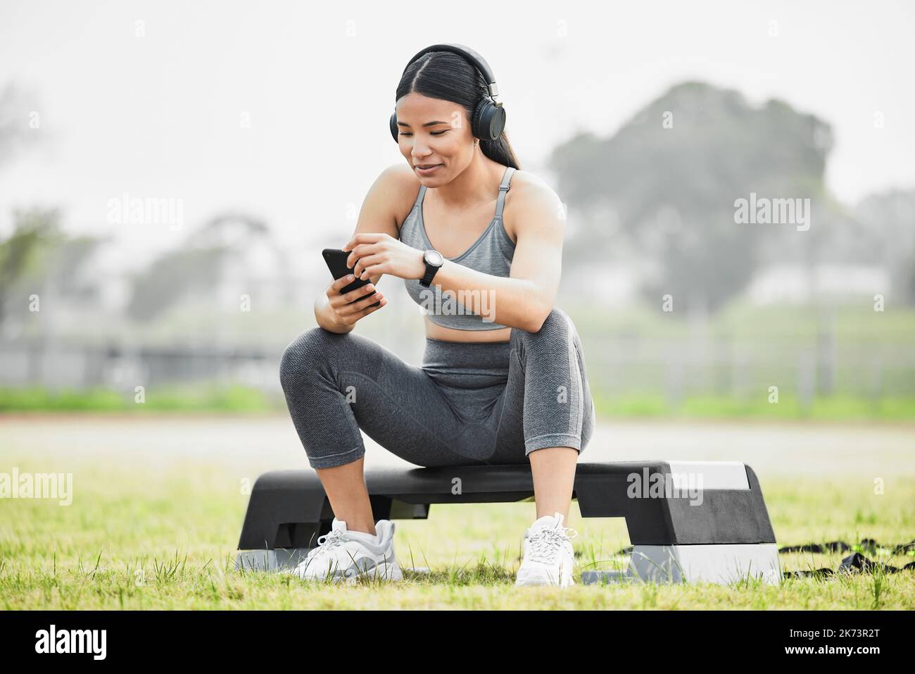 Lets see how I did...Full length shot of an attractive young female athlete checking her ...