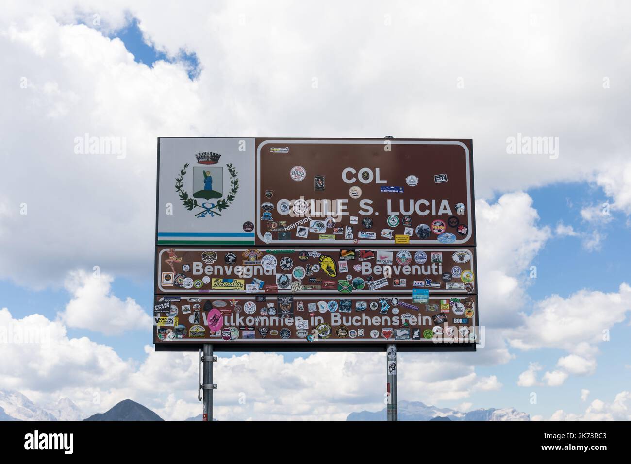 Road sign Colle Santa Lucia at the Passo Giau covered in visitors ...