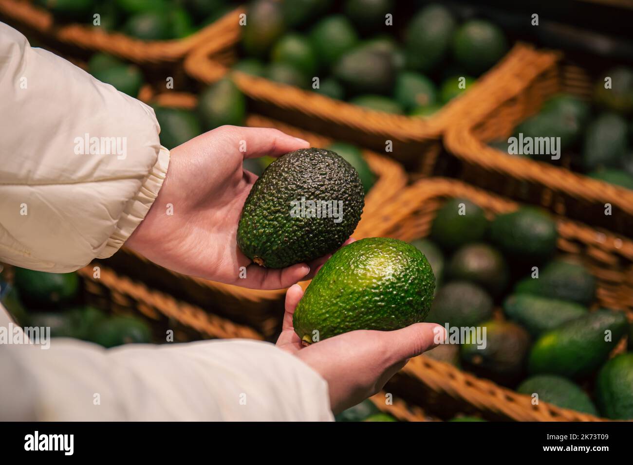 A woman chooses an avocado in a grocery store Stock Photo - Alamy