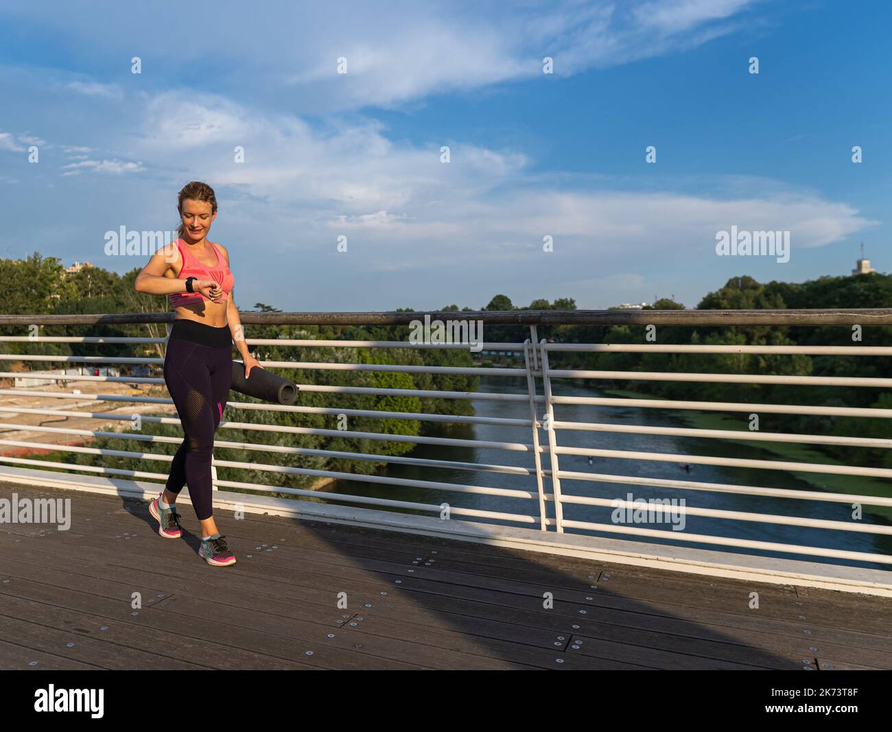 Sporty woman walking looks at her smartwatch in the city center Stock ...