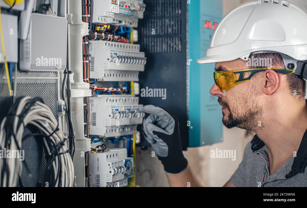 Man, an electrical technician working in a switchboard with fuses Stock ...