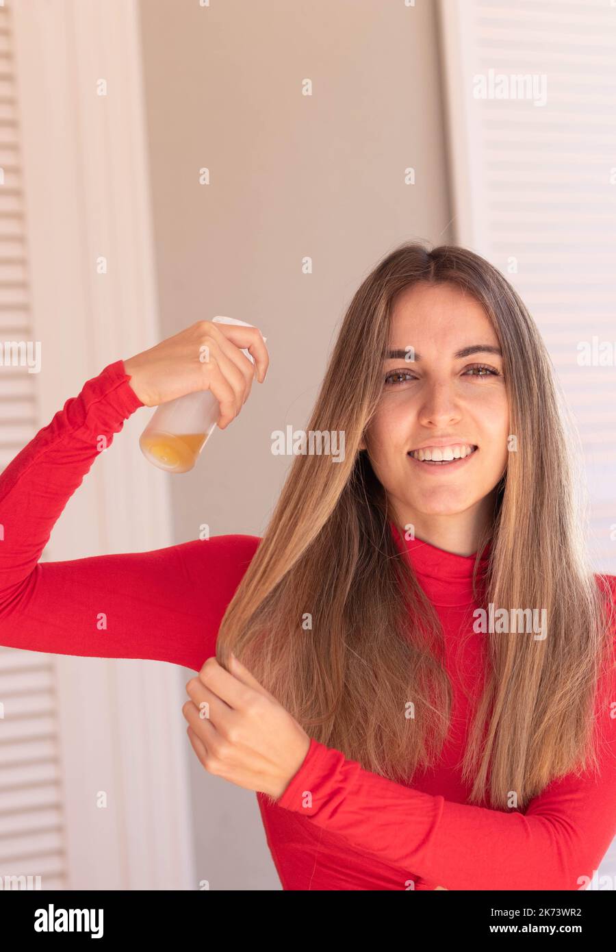 Vertical view of young woman applying spray treatment in the shiny and ...