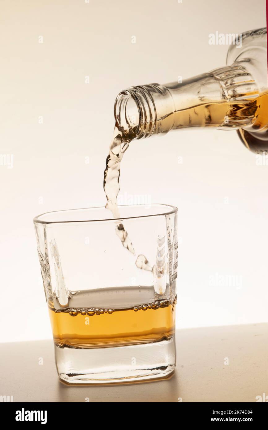 pouring bourbon whiskey into a glass close-up white background vertical ...