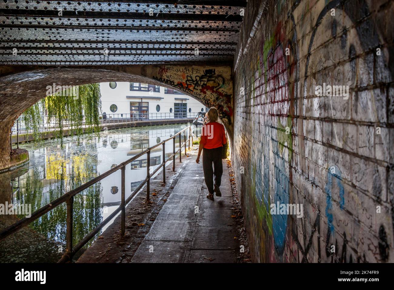 A woman walks along the Regents Canal towpath beneath the Camden Road ...