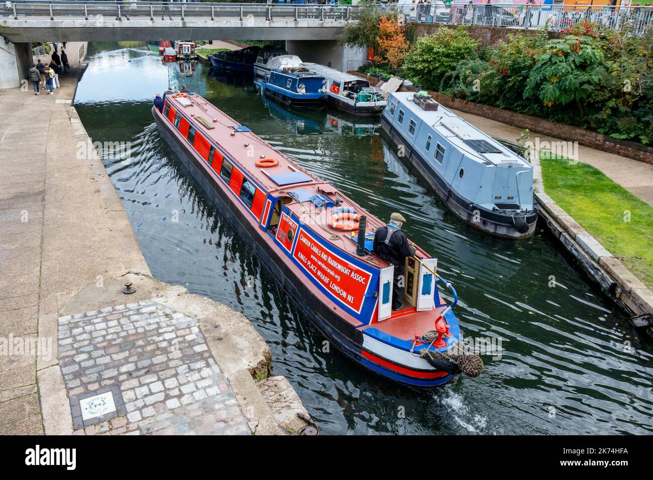 A narrowboat providing tours passes below a bridge on Regents Canal at ...