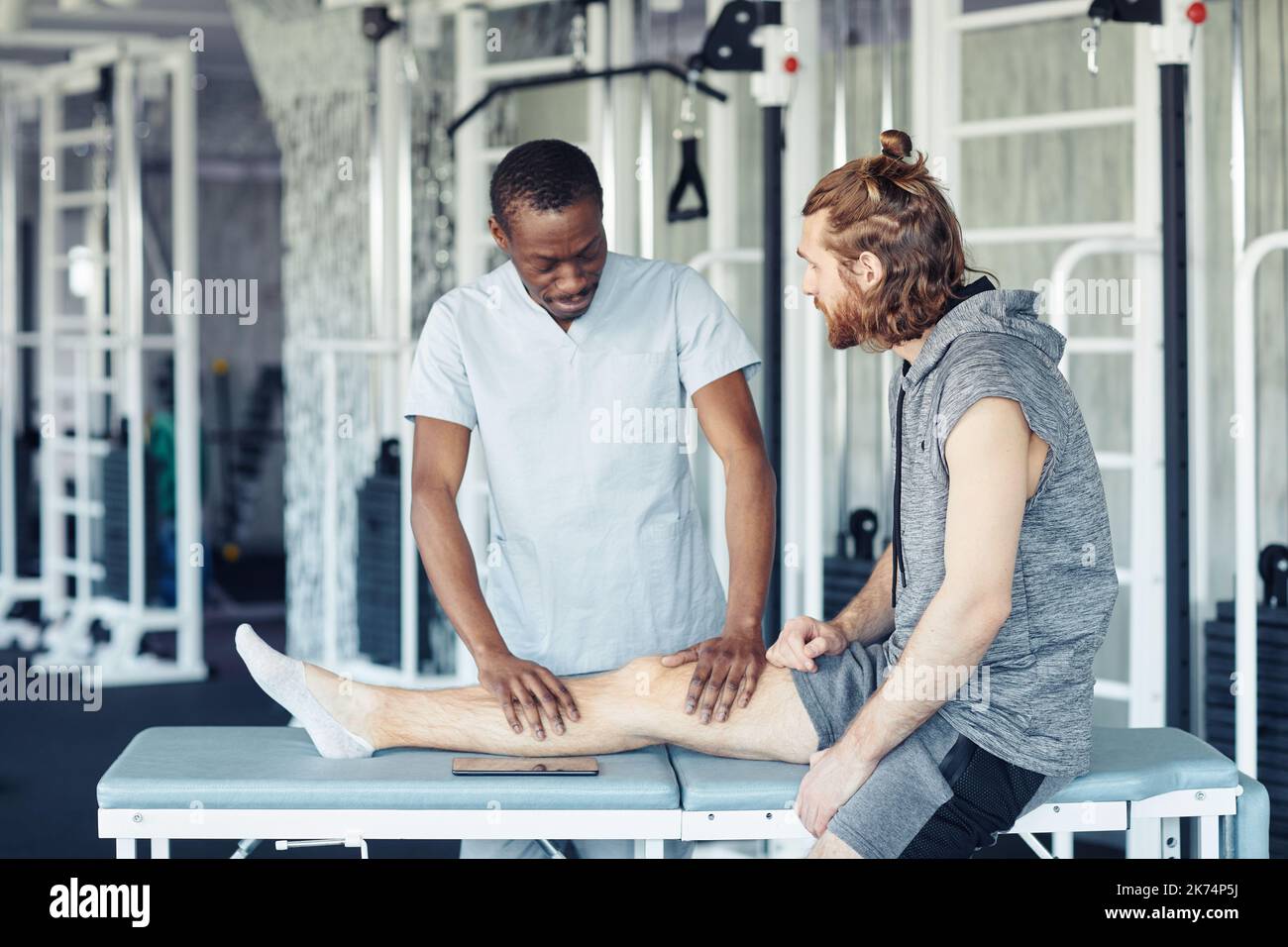 African doctor making massage on leg to patient during his ...