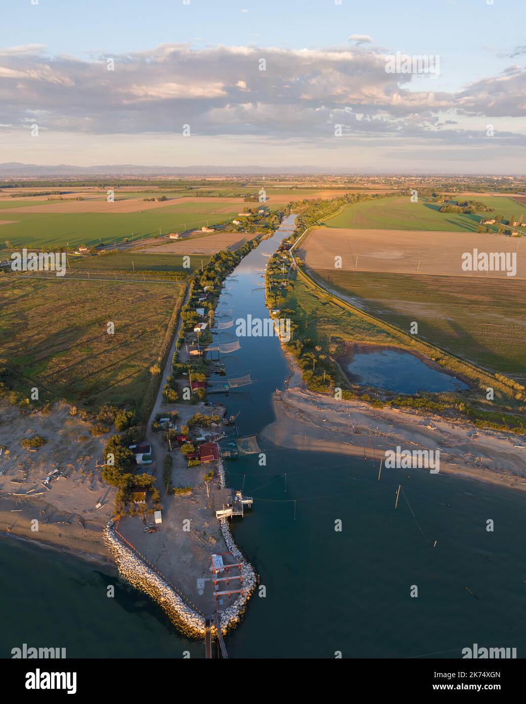 Aerial view of fishing huts on shores of estuary at sunset,italian ...