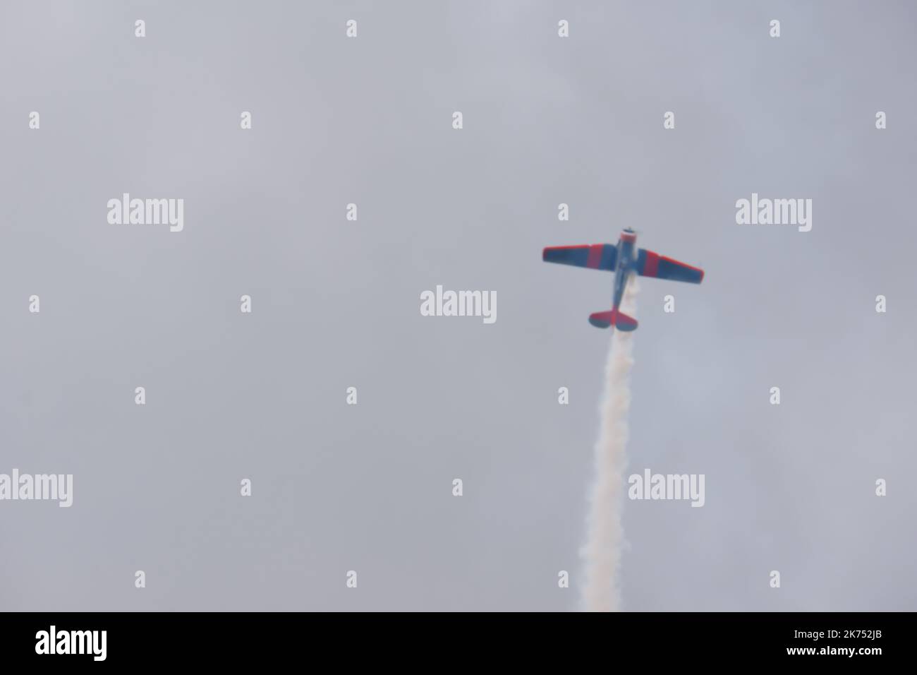 Small plane flying at a cloudy weather with smoke at back for an ...