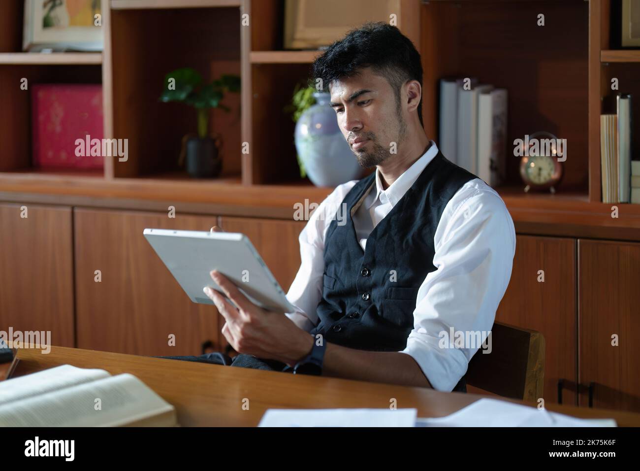 A portrait of a good looking and discreet Asian man sitting at his desk ...