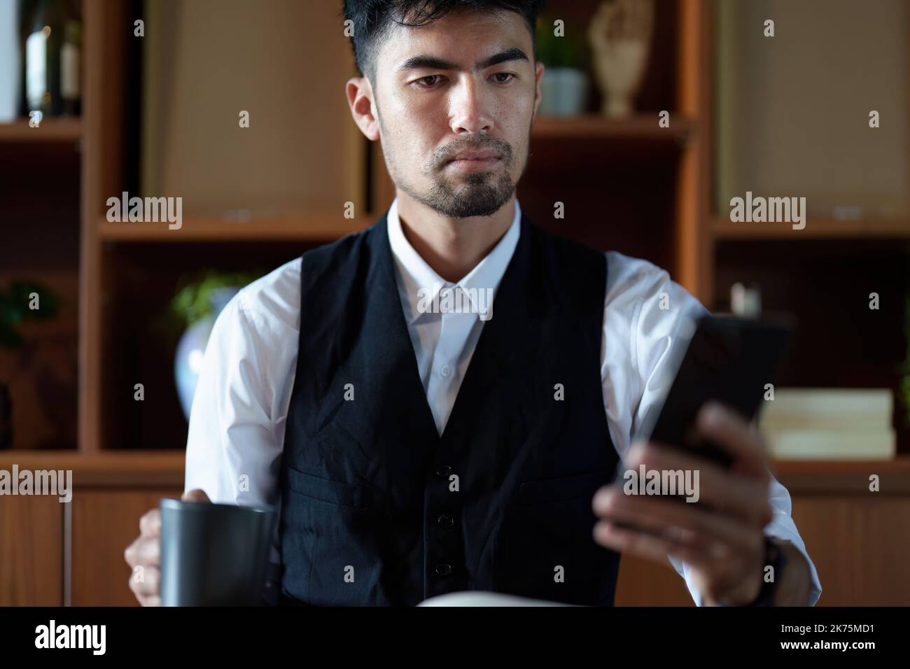 A portrait of a handsome and discreet Asian man sitting at his desk ...