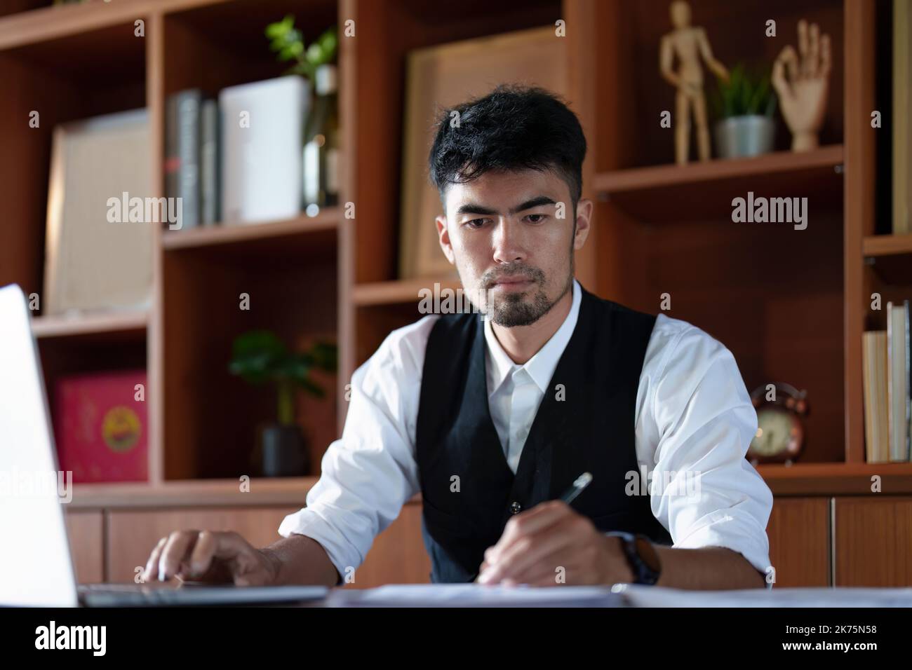 A portrait of a good-looking and discreet Asian man sitting at his desk ...