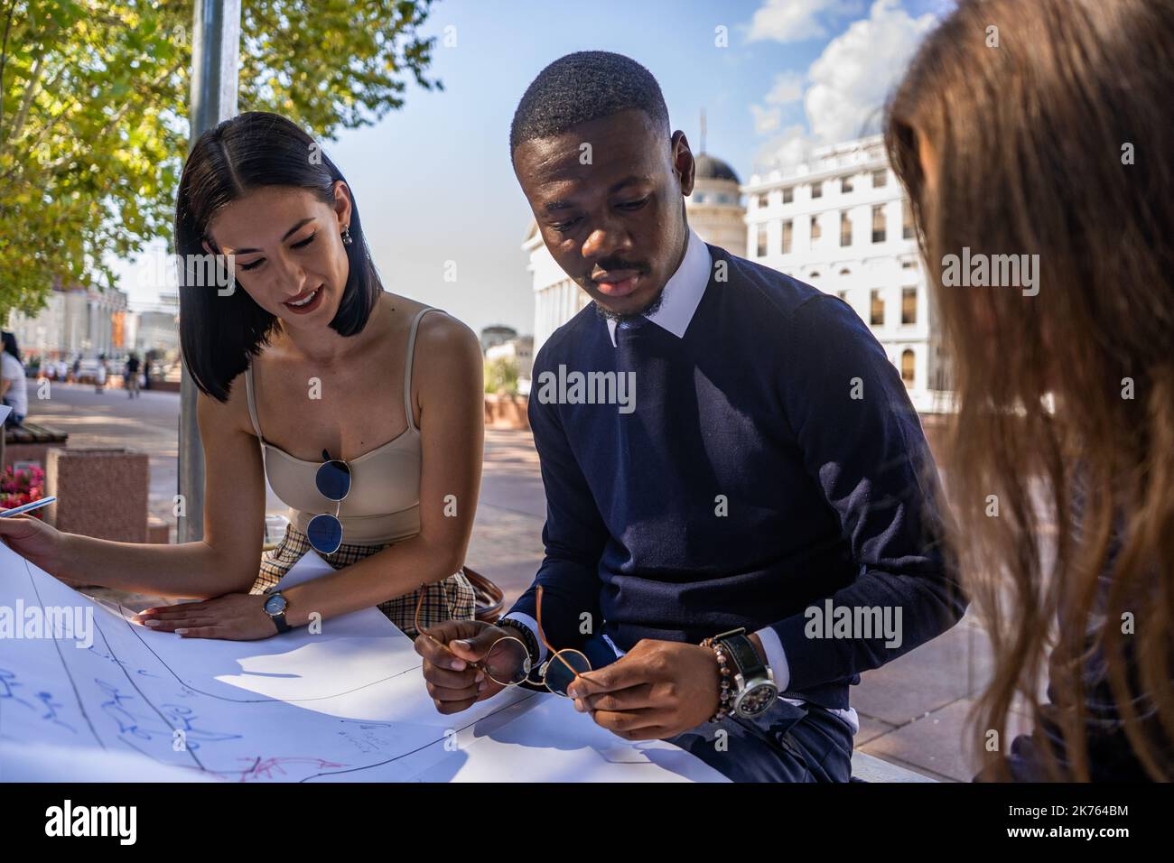 Three business people are looking at the new plan together while ...