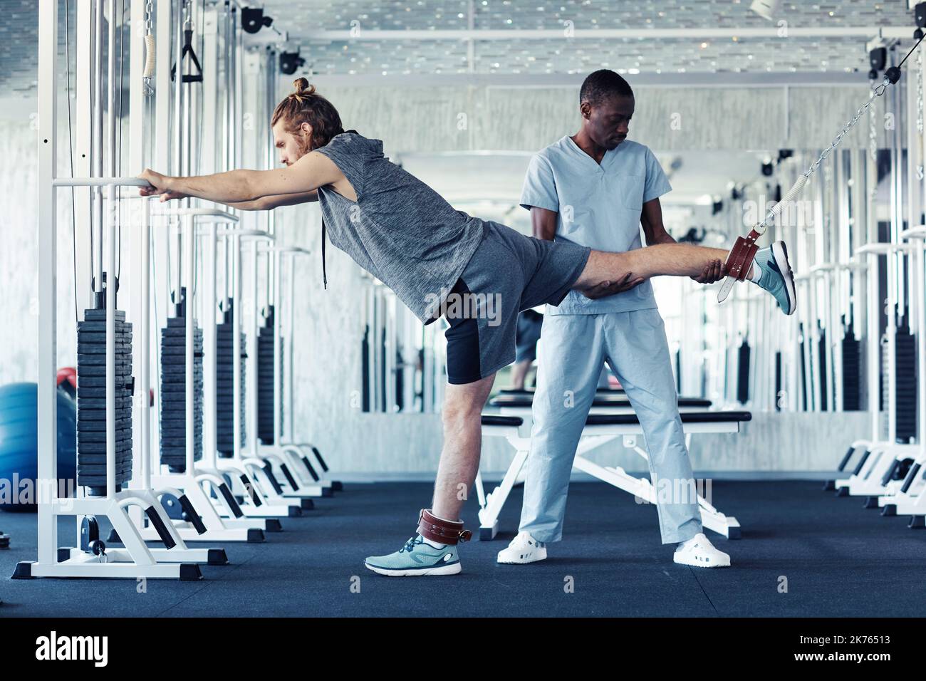 Young patient exercising in gym with the help of therapist during ...