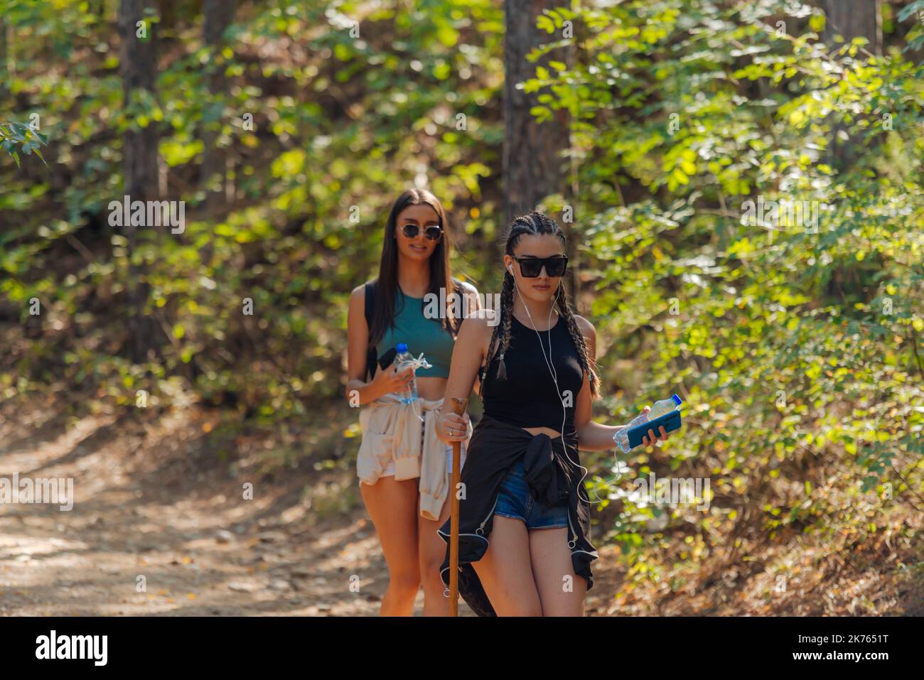 Sisters hiking through beautiful woods while wearing a backpack and ...