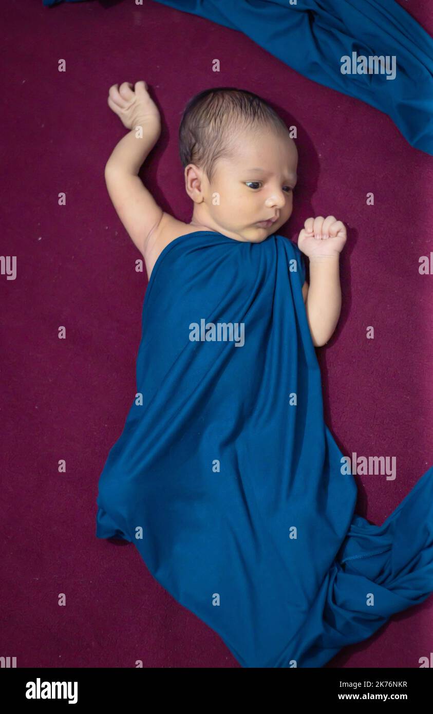 newly born baby laying on red velvet cloth with cute facial expression ...