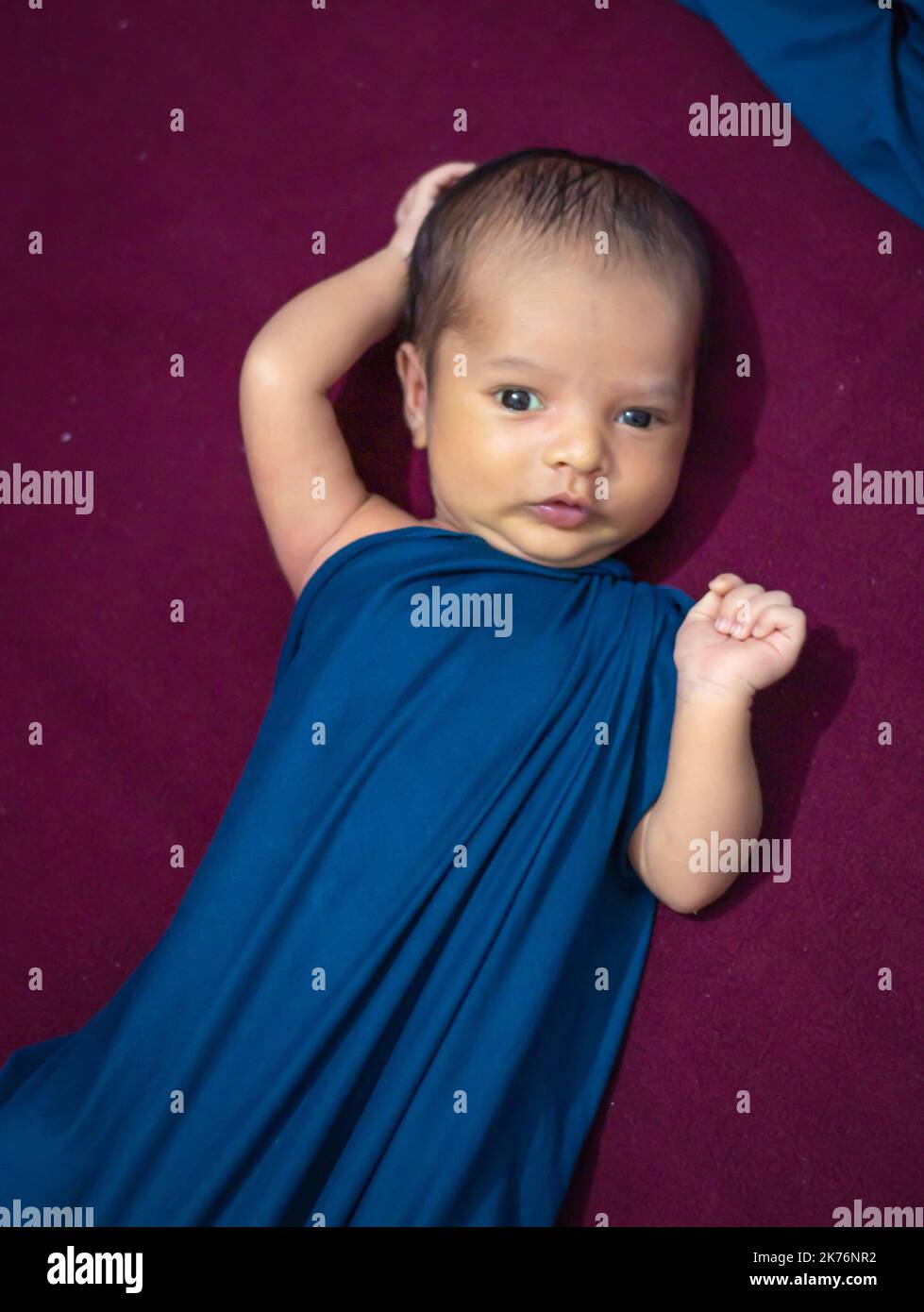 newly born baby laying on red velvet cloth with cute facial expression from different angle ...