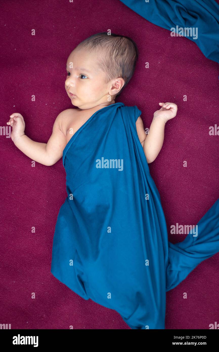 newly born baby laying on red velvet cloth with cute facial expression ...