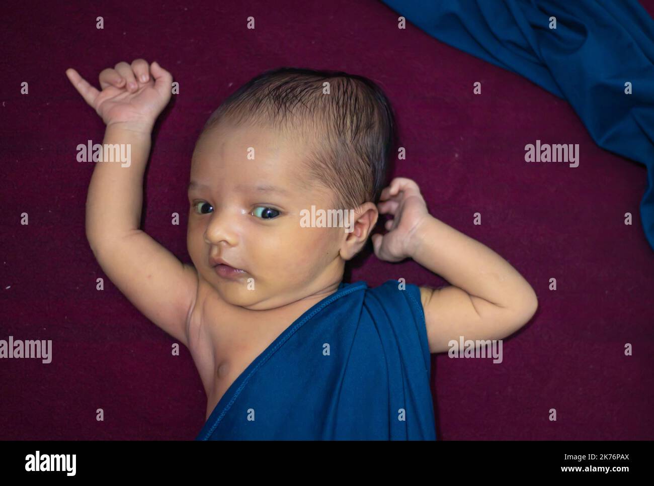newly born baby laying on red velvet cloth with cute facial expression from different angle ...