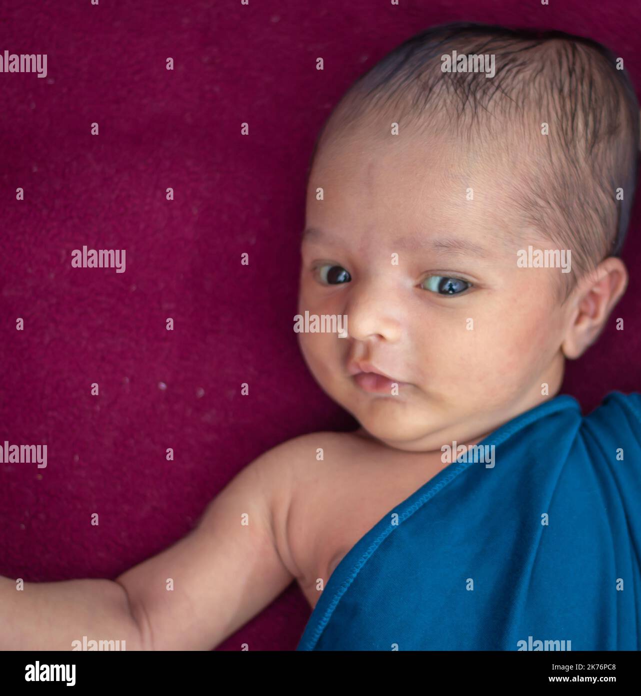 newly born baby laying on red velvet cloth with cute facial expression from different angle ...