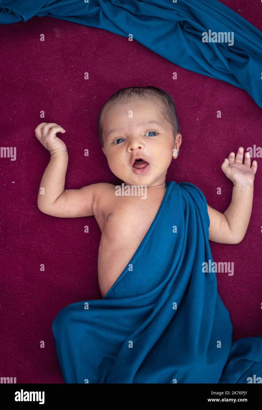 newly born baby laying on red velvet cloth with cute facial expression ...