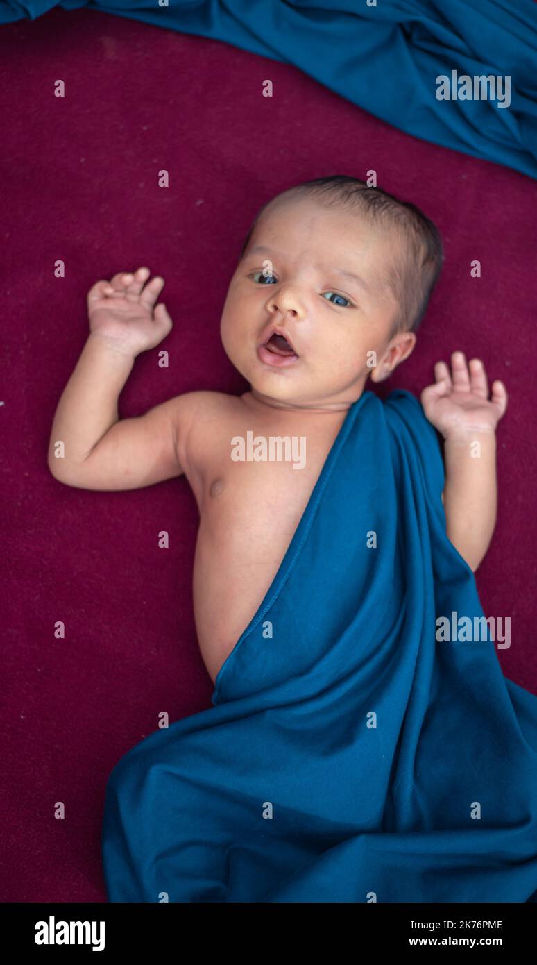 newly born baby laying on red velvet cloth with cute facial expression from different angle ...