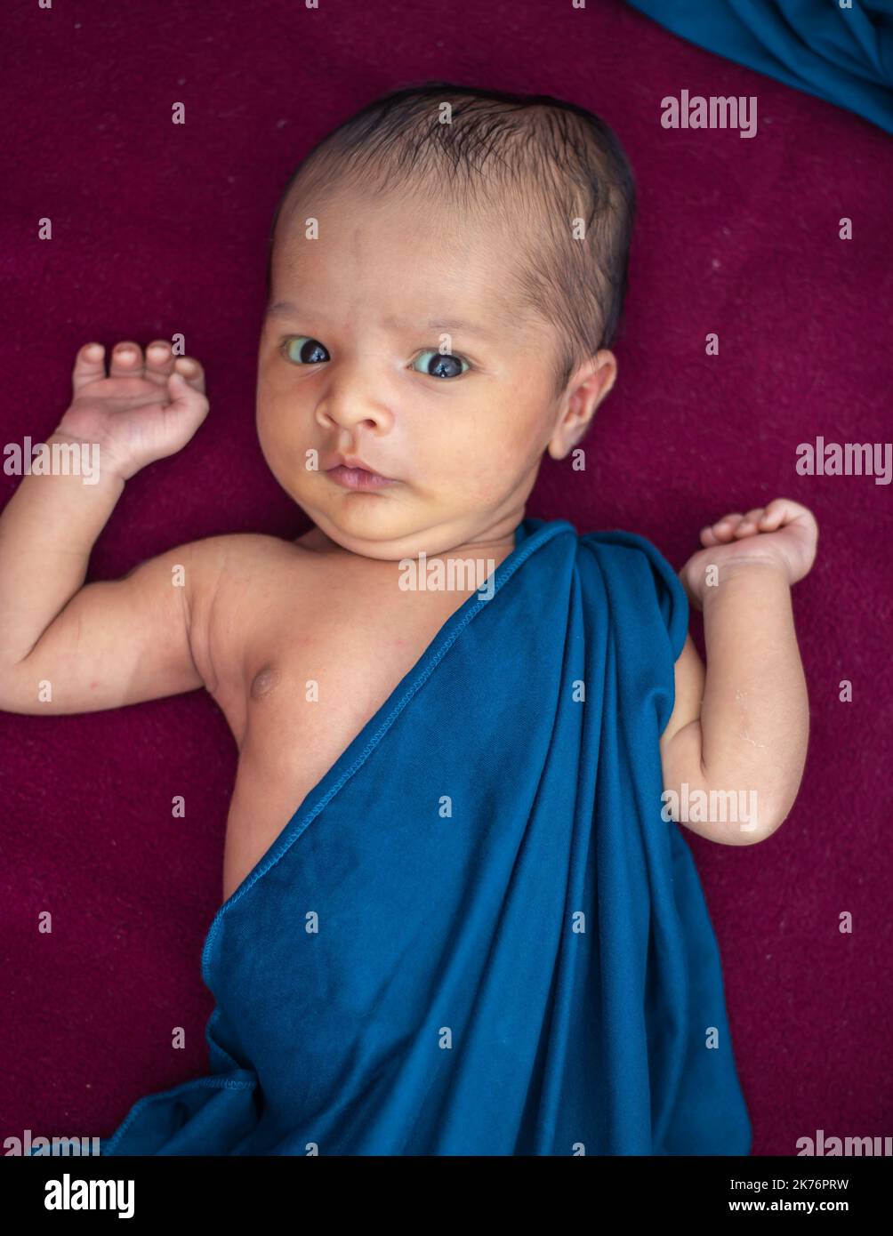 newly born baby laying on red velvet cloth with cute facial expression from different angle ...