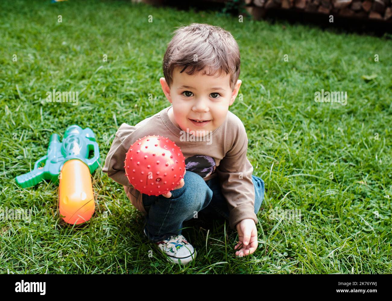 a young boy is Playing with a ball in the backyard Stock Photo - Alamy