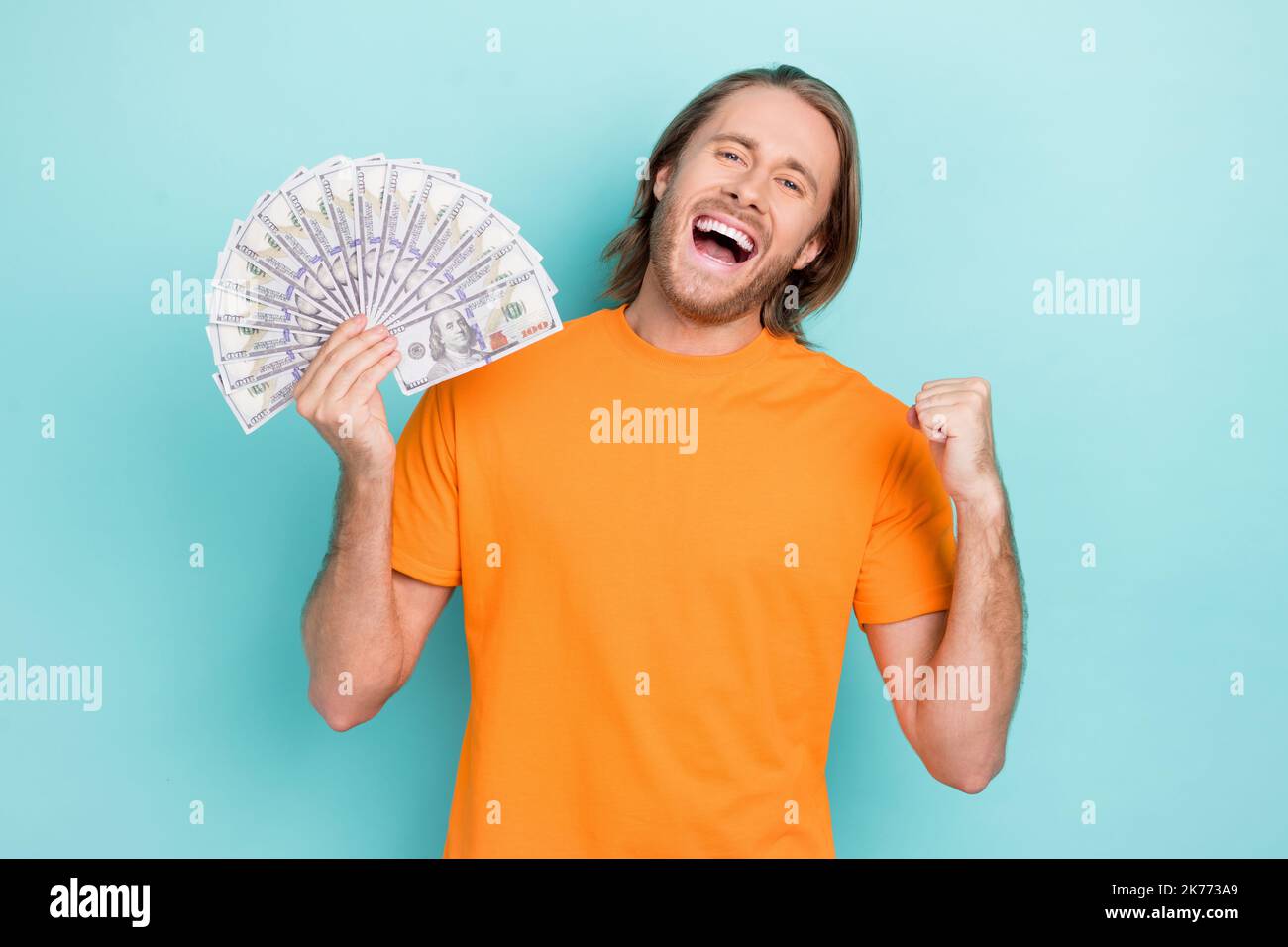 Photo of excited lucky guy dressed orange t-shirt rising money fist ...