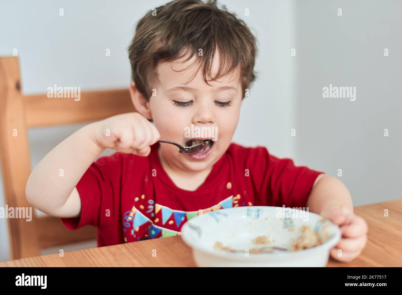 a boy is having fun at the breakfast table eating oatmeal Stock Photo ...