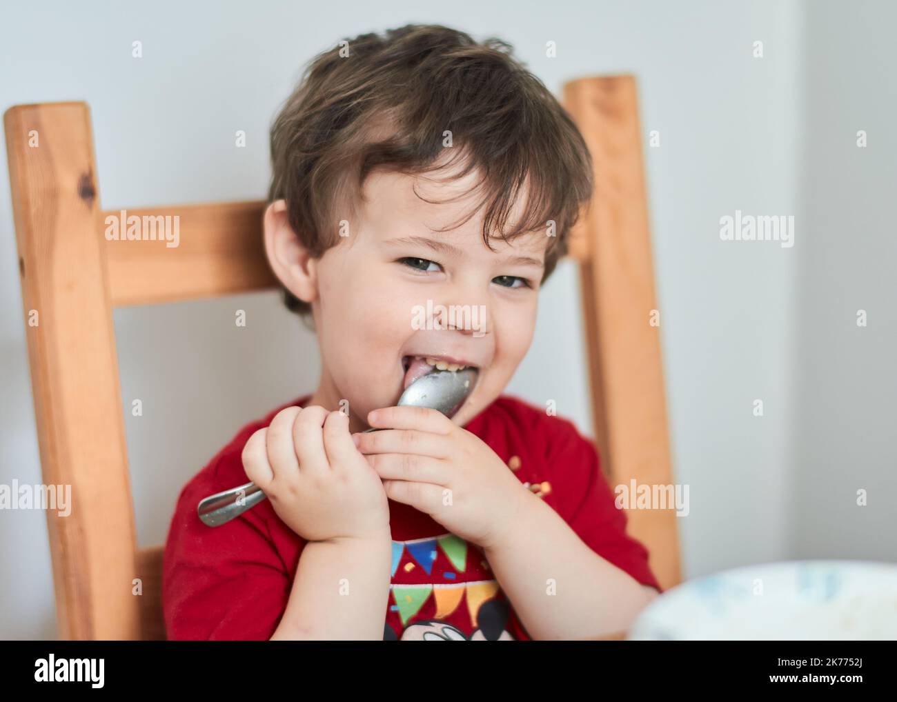 a boy is having fun at the breakfast table eating oatmeal Stock Photo ...