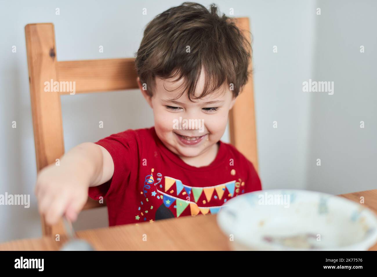 a boy is having fun at the breakfast table eating oatmeal Stock Photo ...