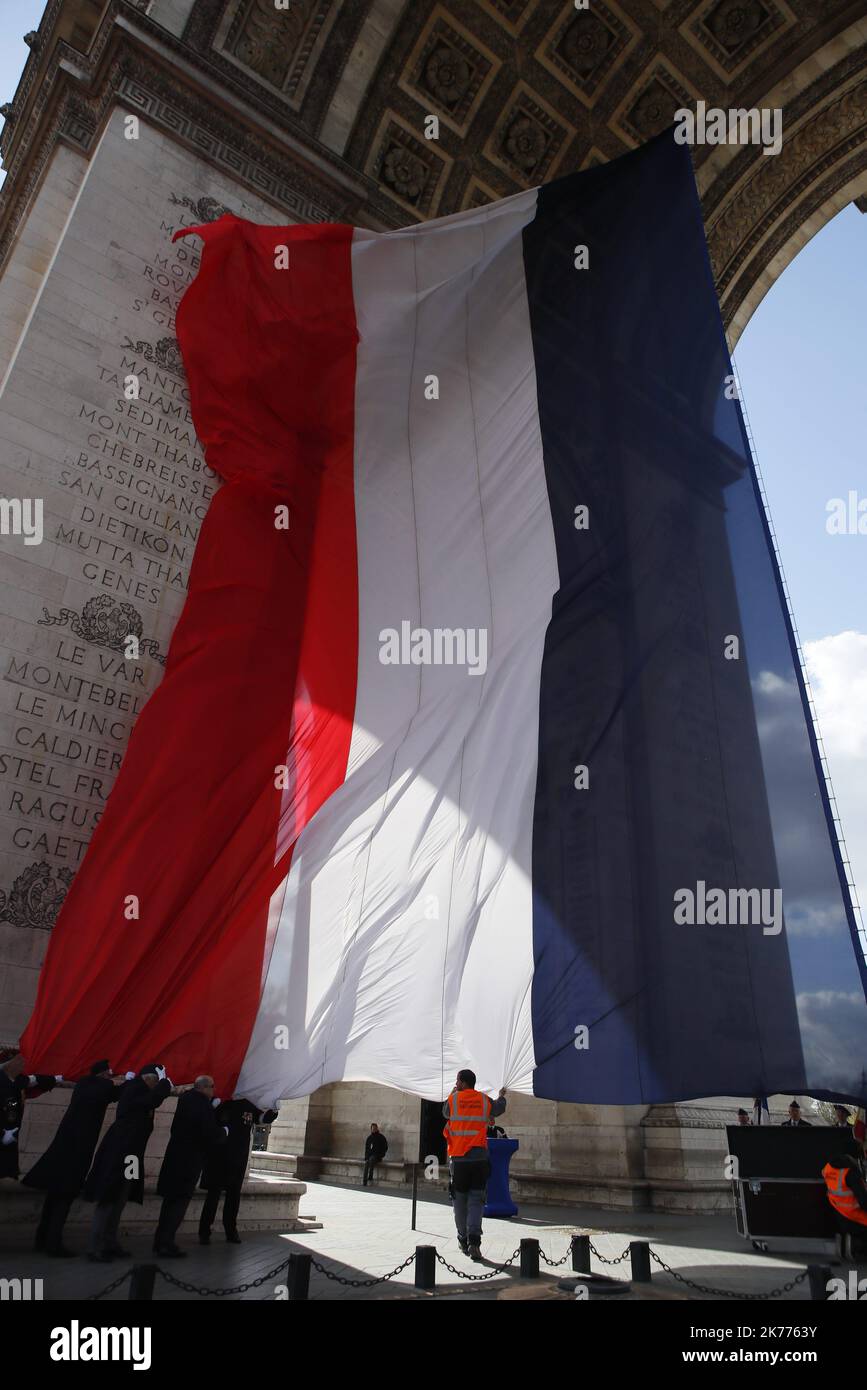 Workers set up a giant French national flag under the Arc de Triomphe ...